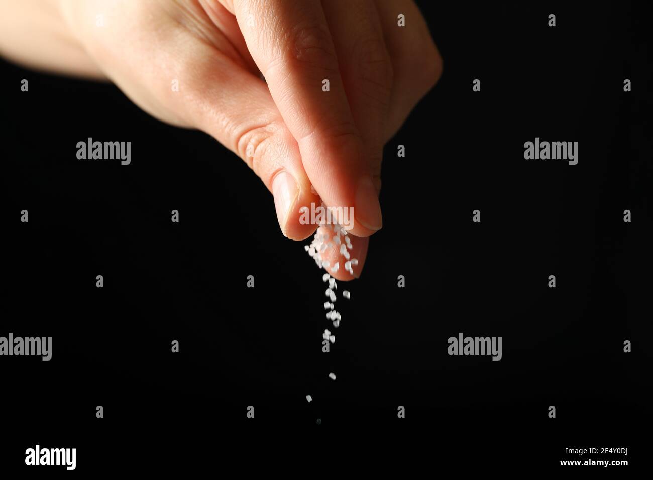 Female hand adding salt on black background Stock Photo - Alamy