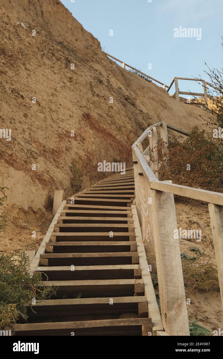 Clay slope with wooden steps against blue sky Stock Photo - Alamy