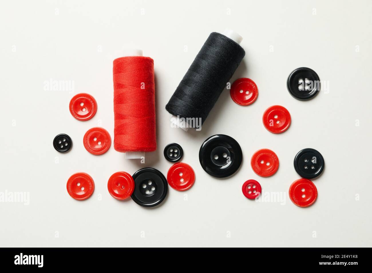 Red and black threads and buttons on white background Stock Photo - Alamy