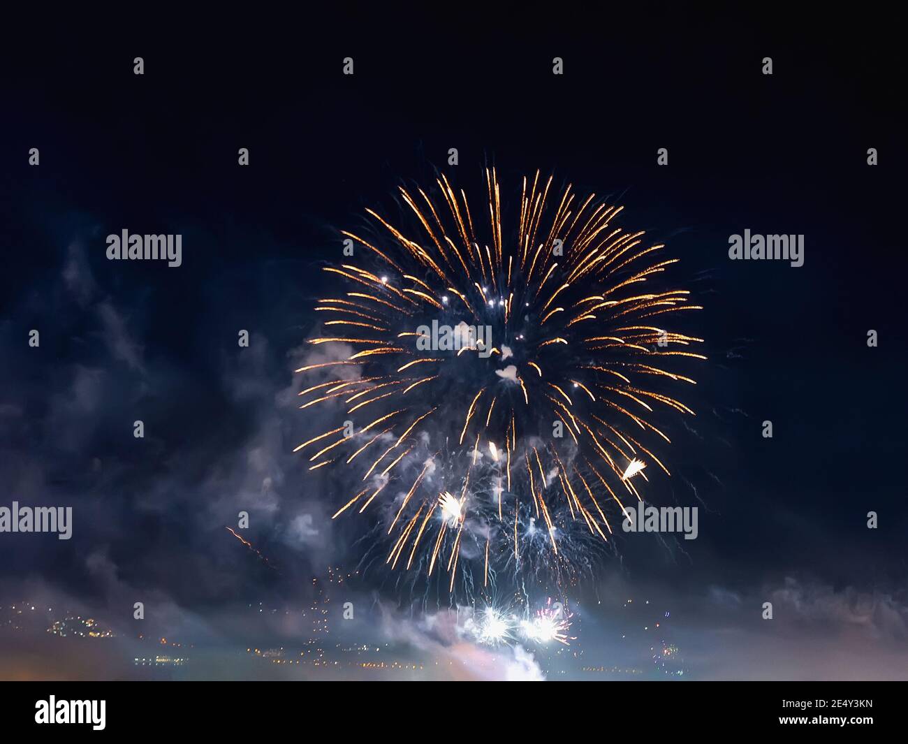 Bright yellow fireworks sparks in the dark sky. Small city celebrates ...