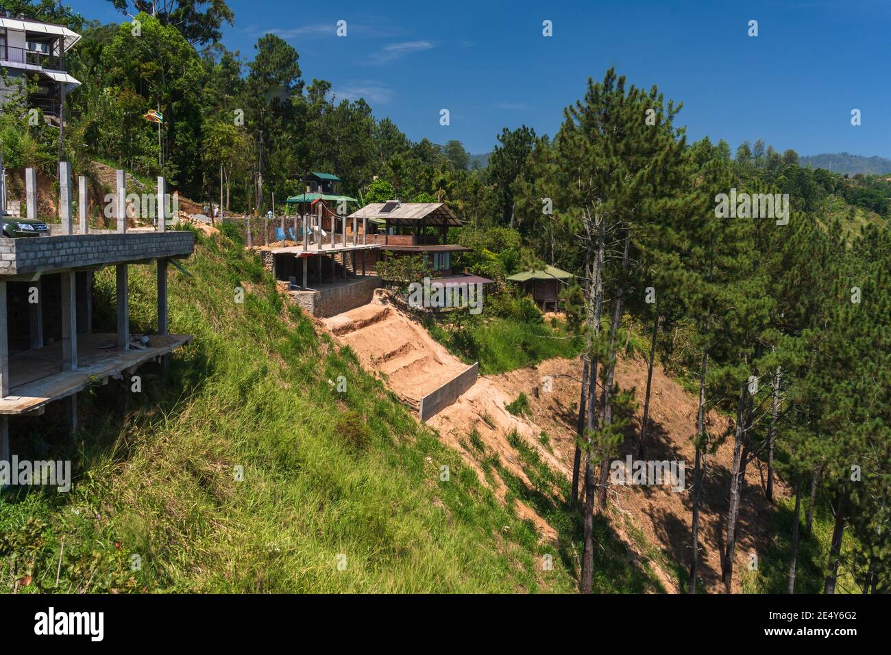 Houses being constructed on a steep green forest slope ina tropical ...