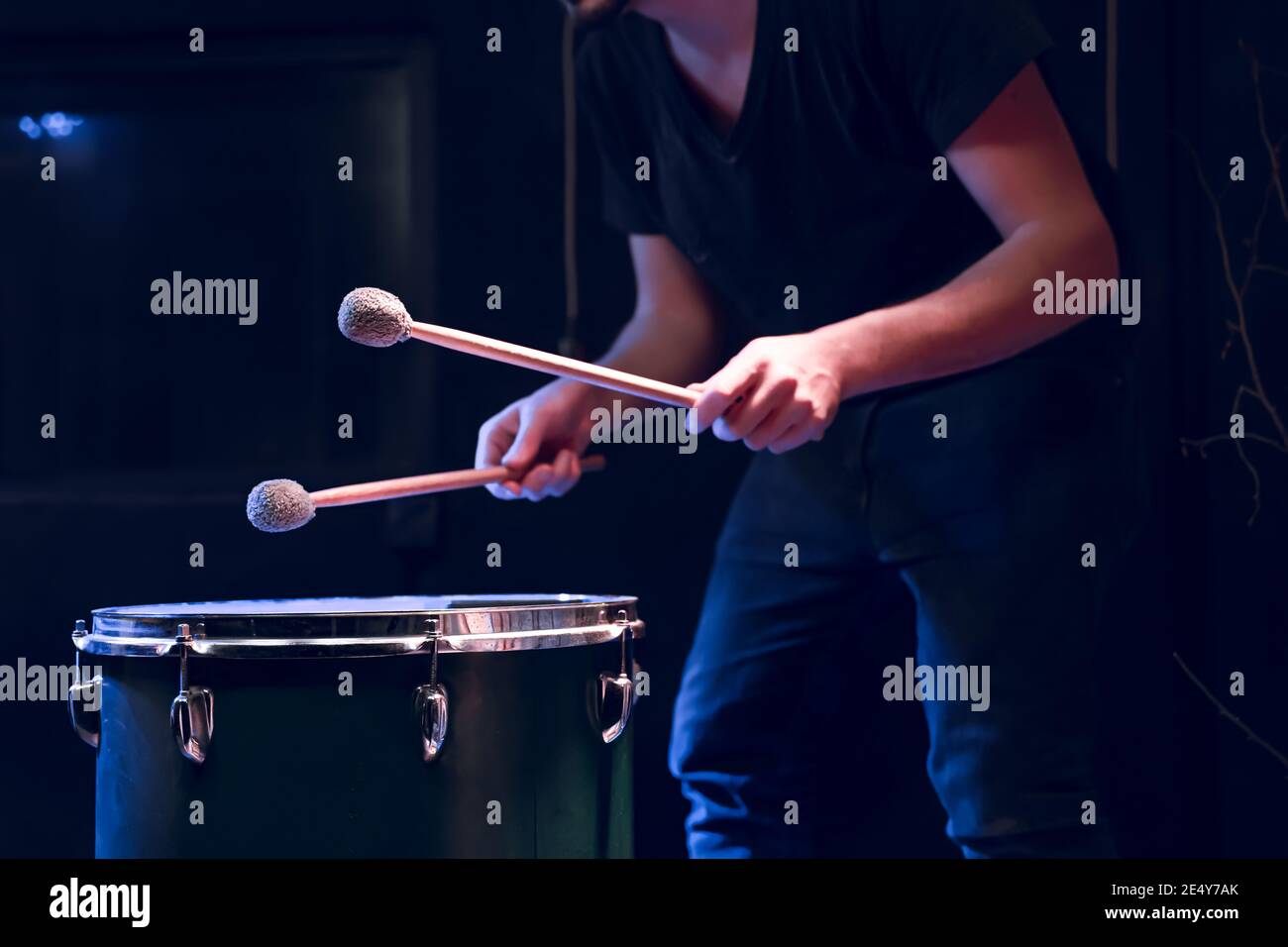 The percussionist plays with sticks on the floor tom in a dark room ...