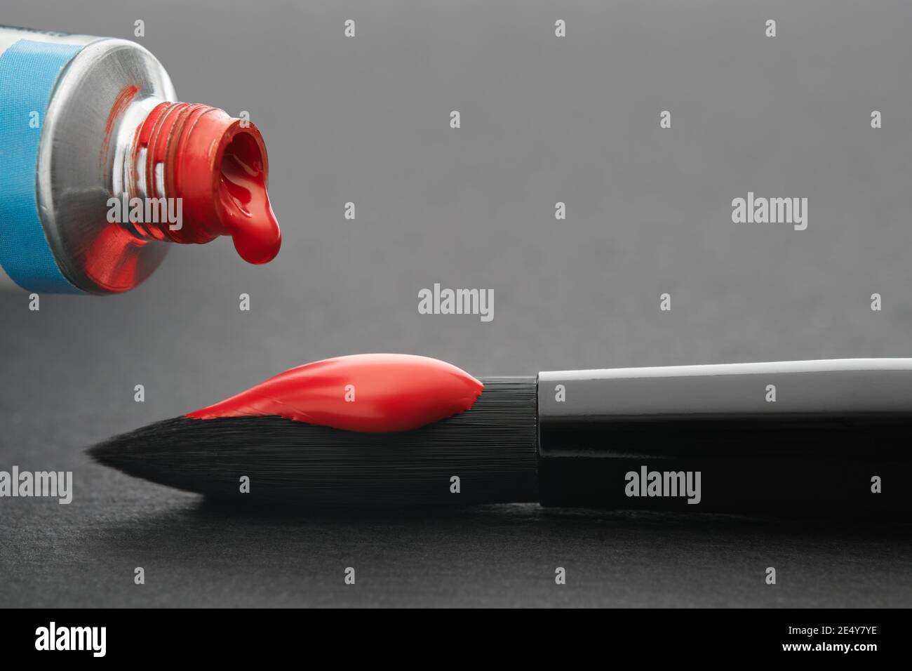 Tube of red watercolor paint and artistic paintbrush for painting with ...