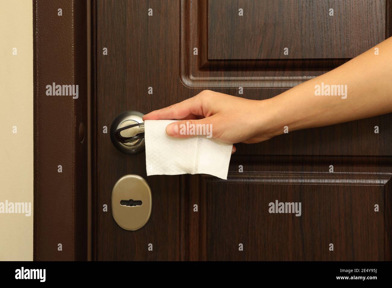 Woman hand using antibacterial wet wipe for disinfecting door handle ...