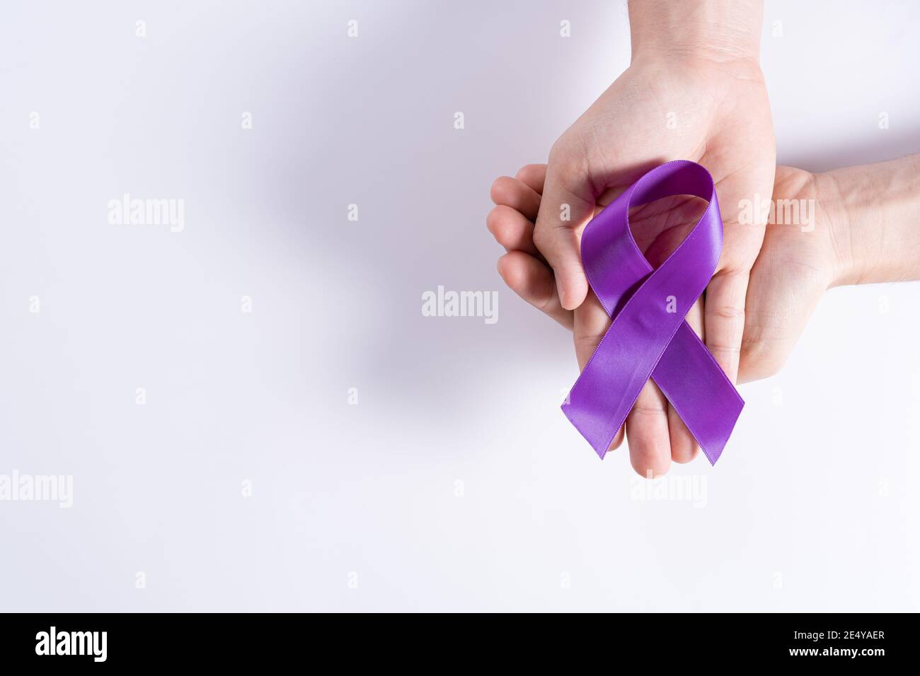 World cancer day, hands holding purple ribbon on grey background with ...