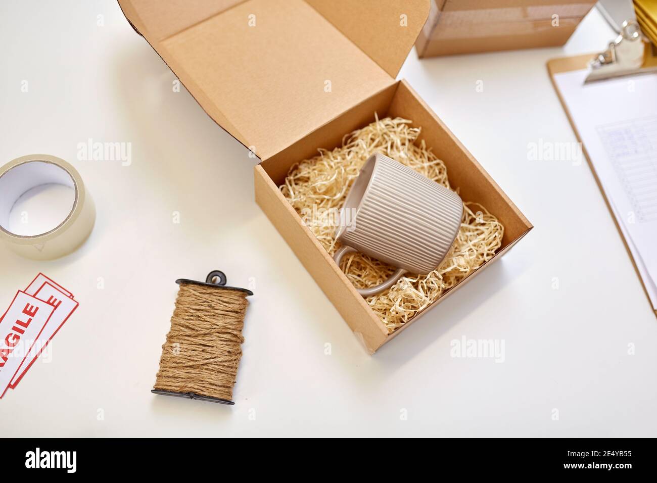 parcel with straw filler and mug at post office Stock Photo - Alamy