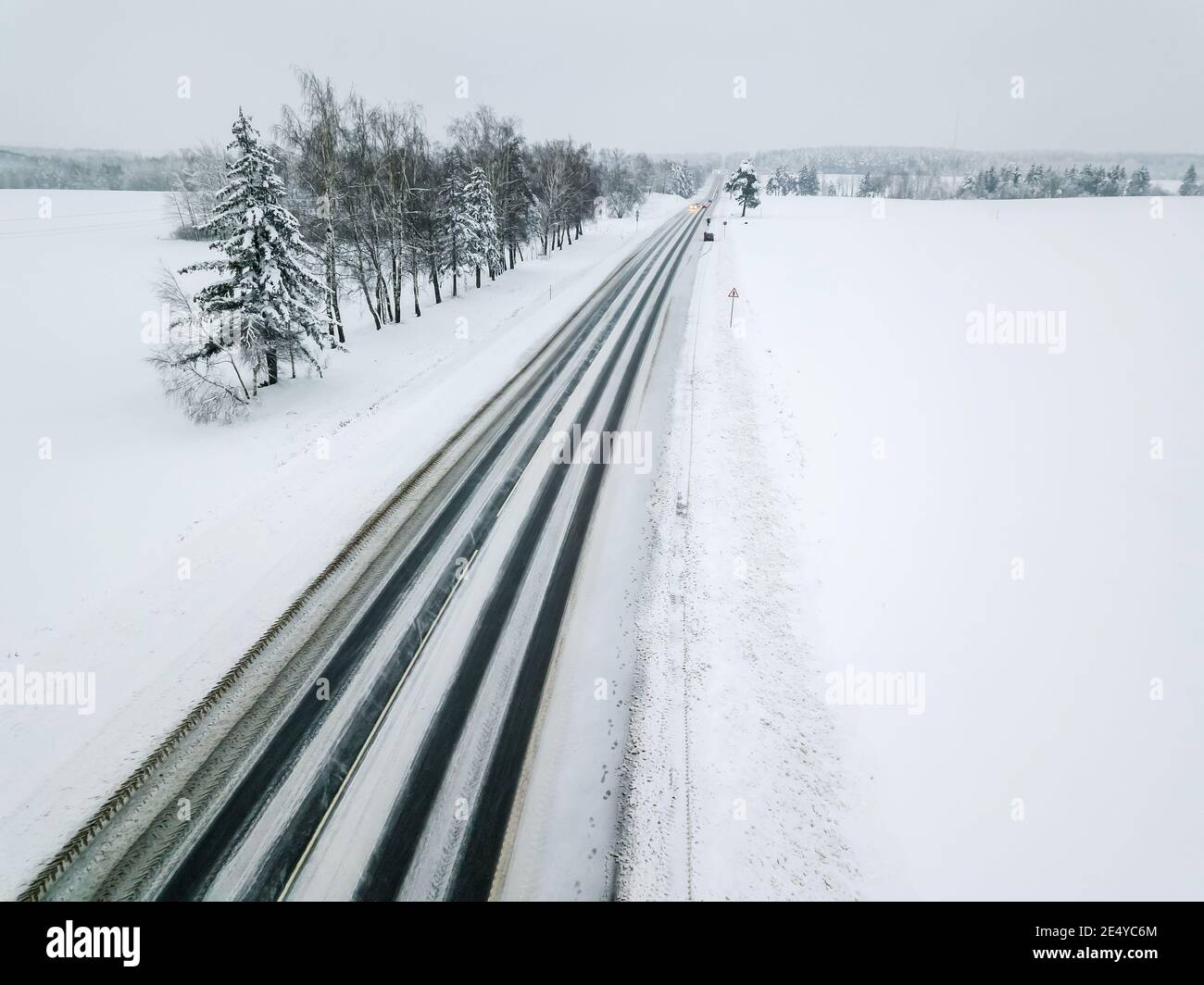 Drone view of a paved road with cars with their headlights on in the ...