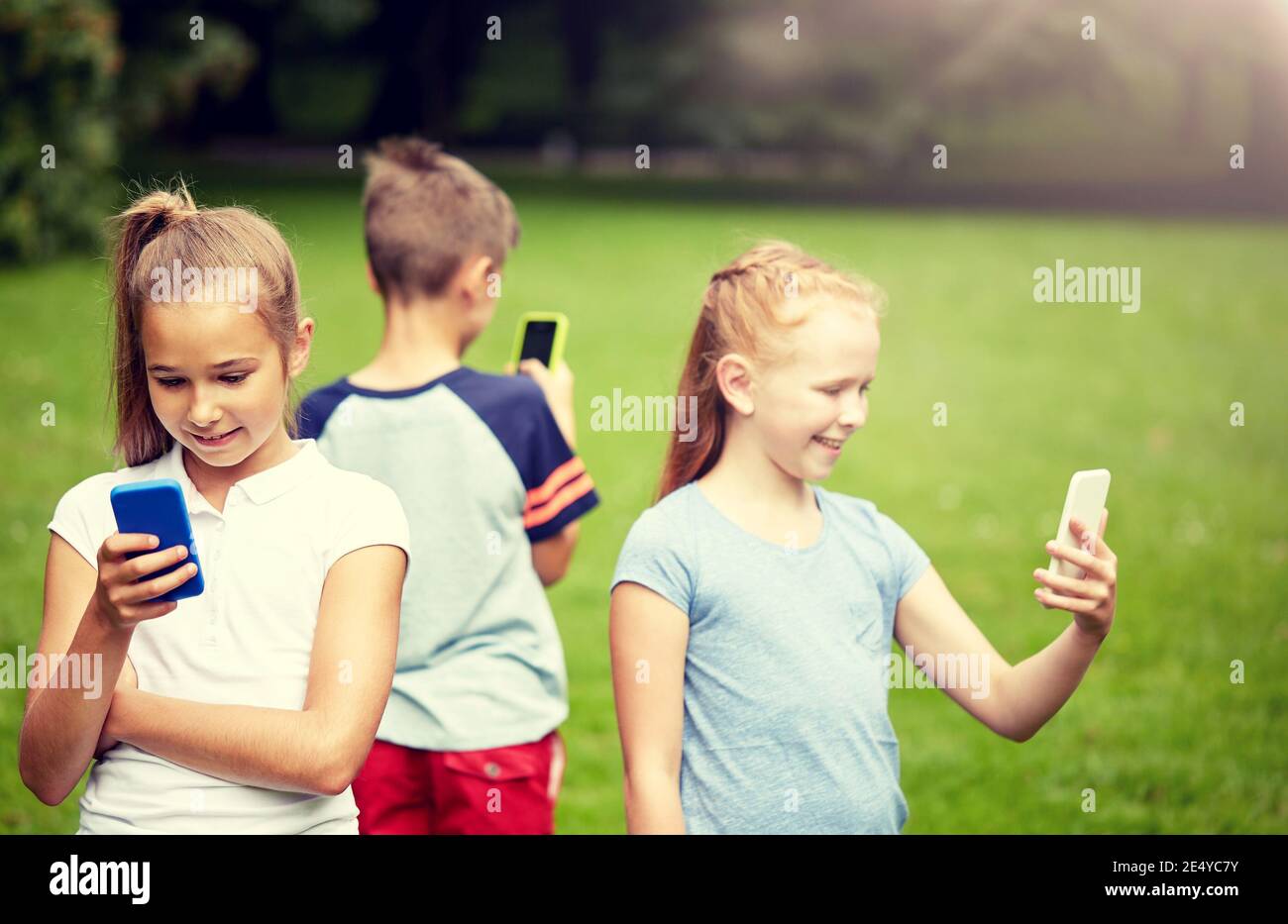 kids with smartphones playing game in summer park Stock Photo - Alamy