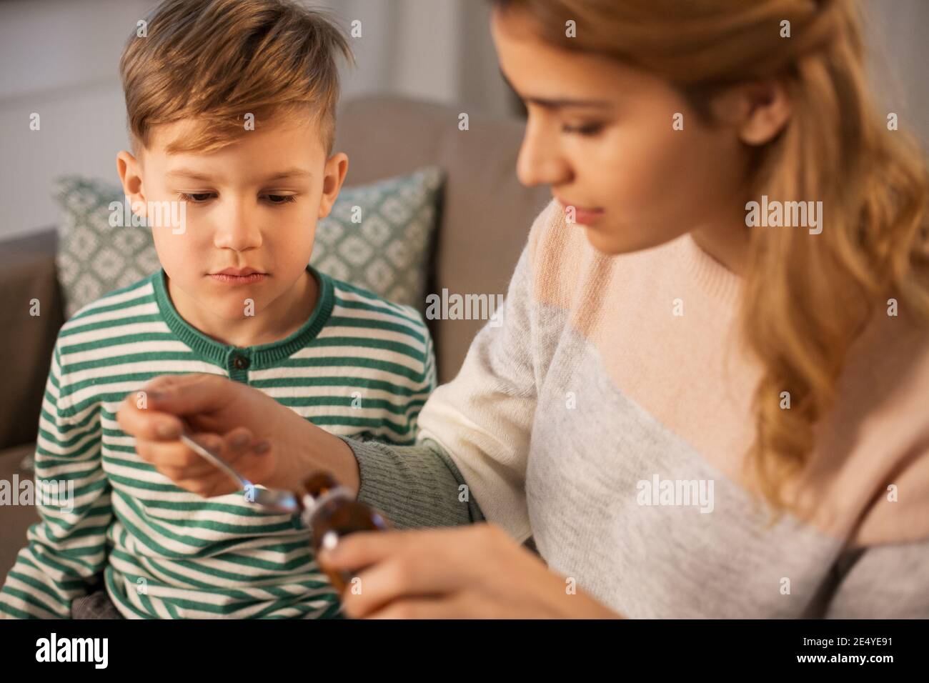 mother giving medication or cough syrup to ill son Stock Photo - Alamy
