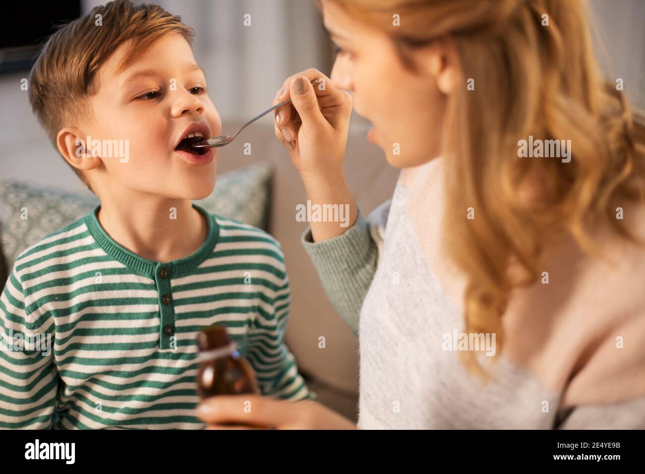 mother giving medication or cough syrup to ill son Stock Photo - Alamy