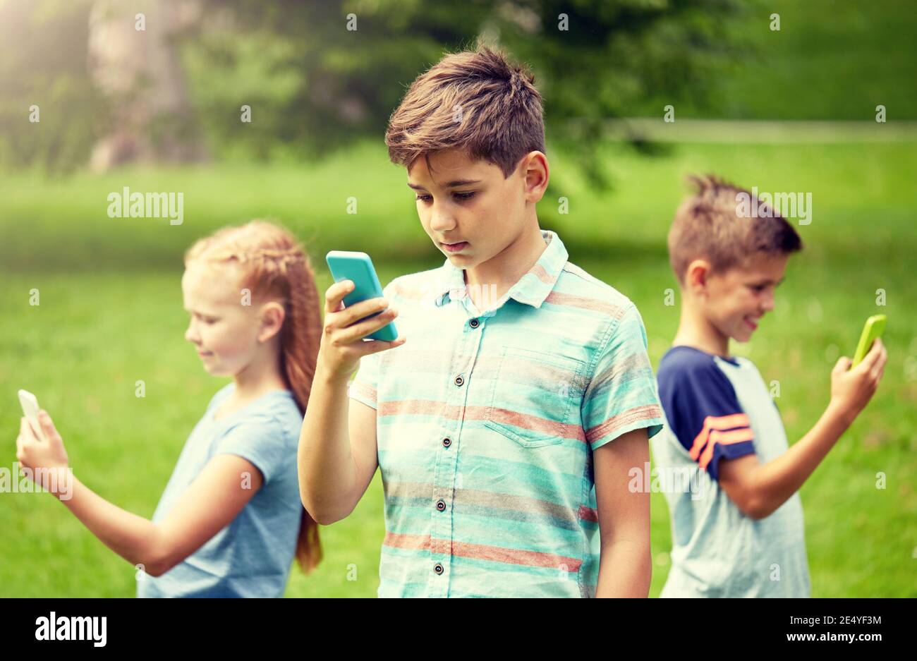 kids with smartphones playing game in summer park Stock Photo - Alamy