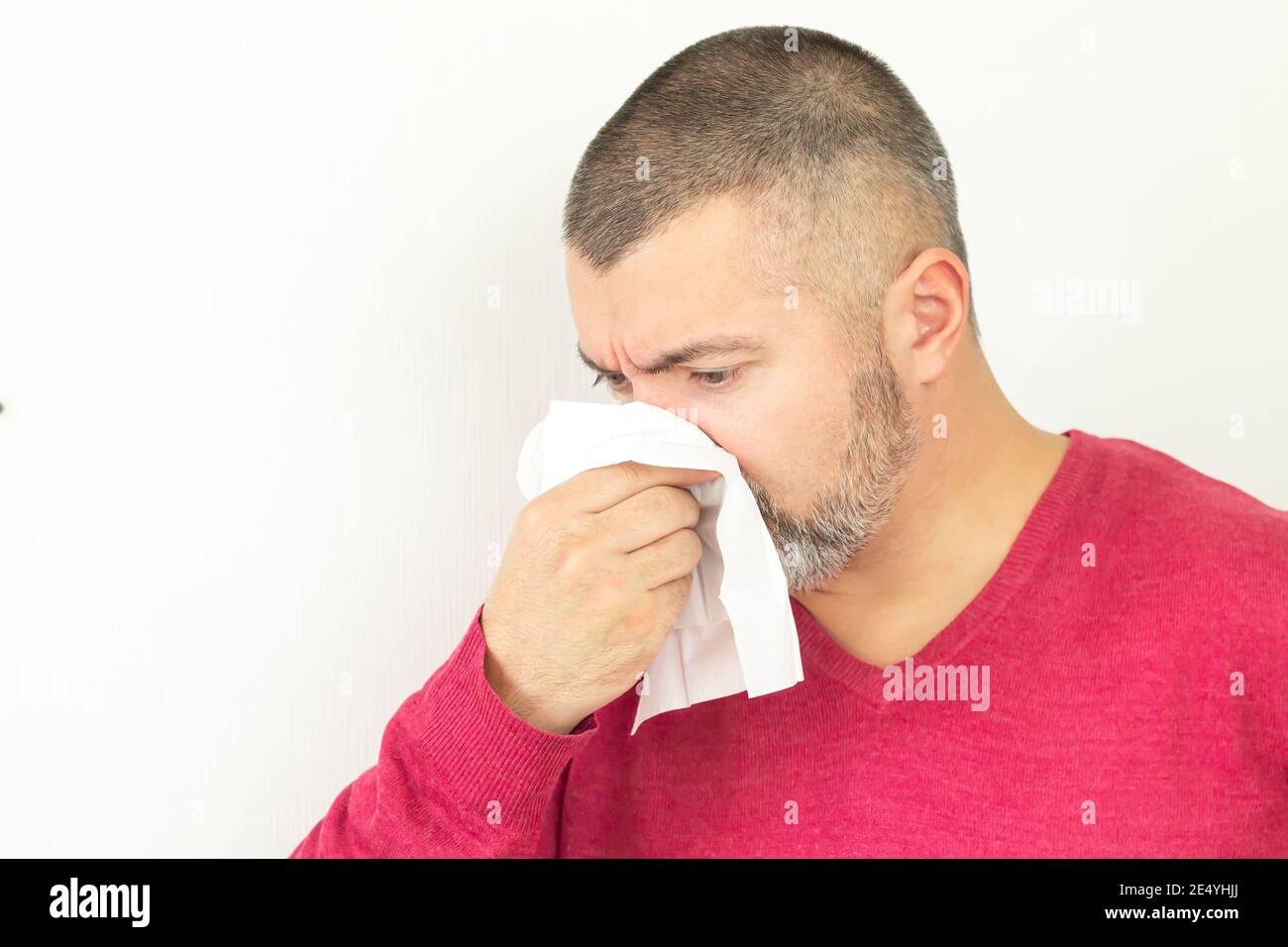 Man holding paper handkerchief and sneezing on white background Stock ...