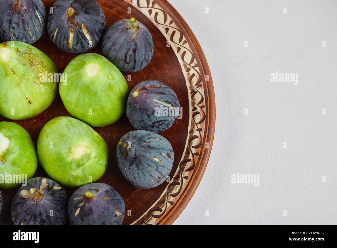 Purple and green figs in a pottery plate Stock Photo - Alamy