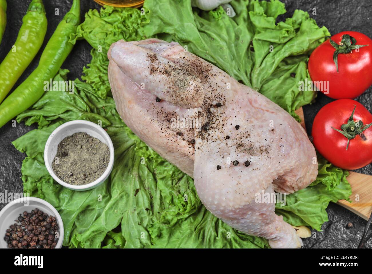 Raw chicken on dark background with bunch of fresh vegetables and ...