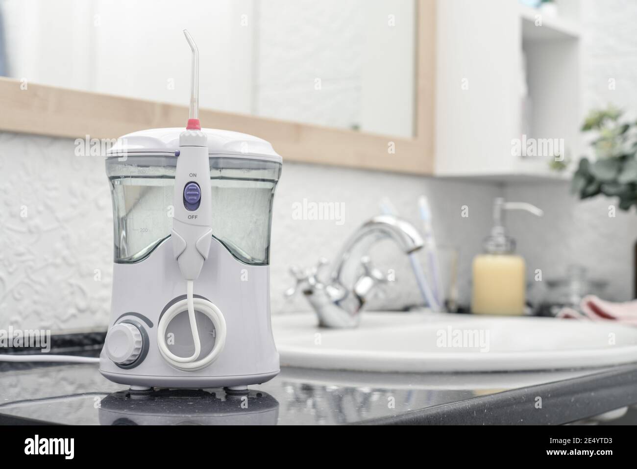 Electric oral irrigator in the white tiled bathroom closeup Stock Photo ...