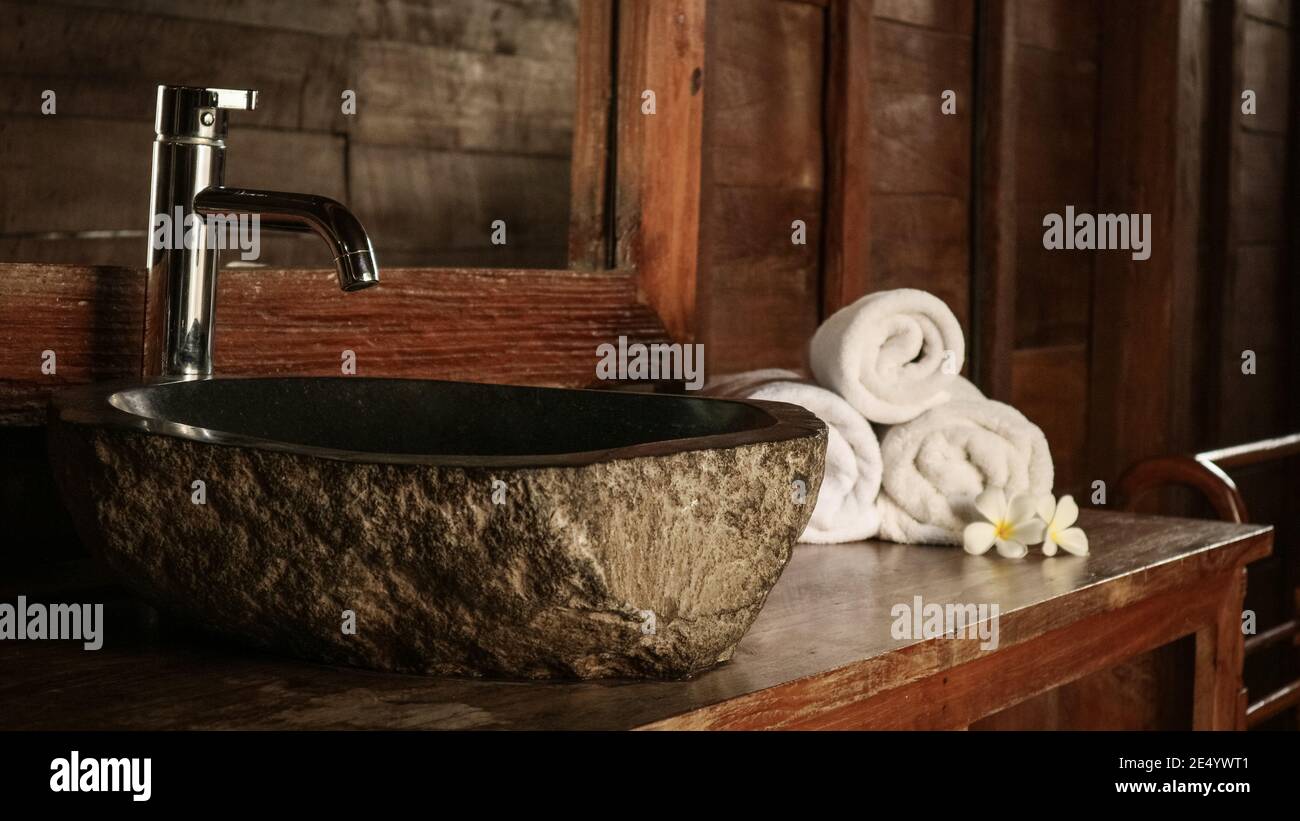 Bathroom with stone washbasin, mirror and towels in traditional ...