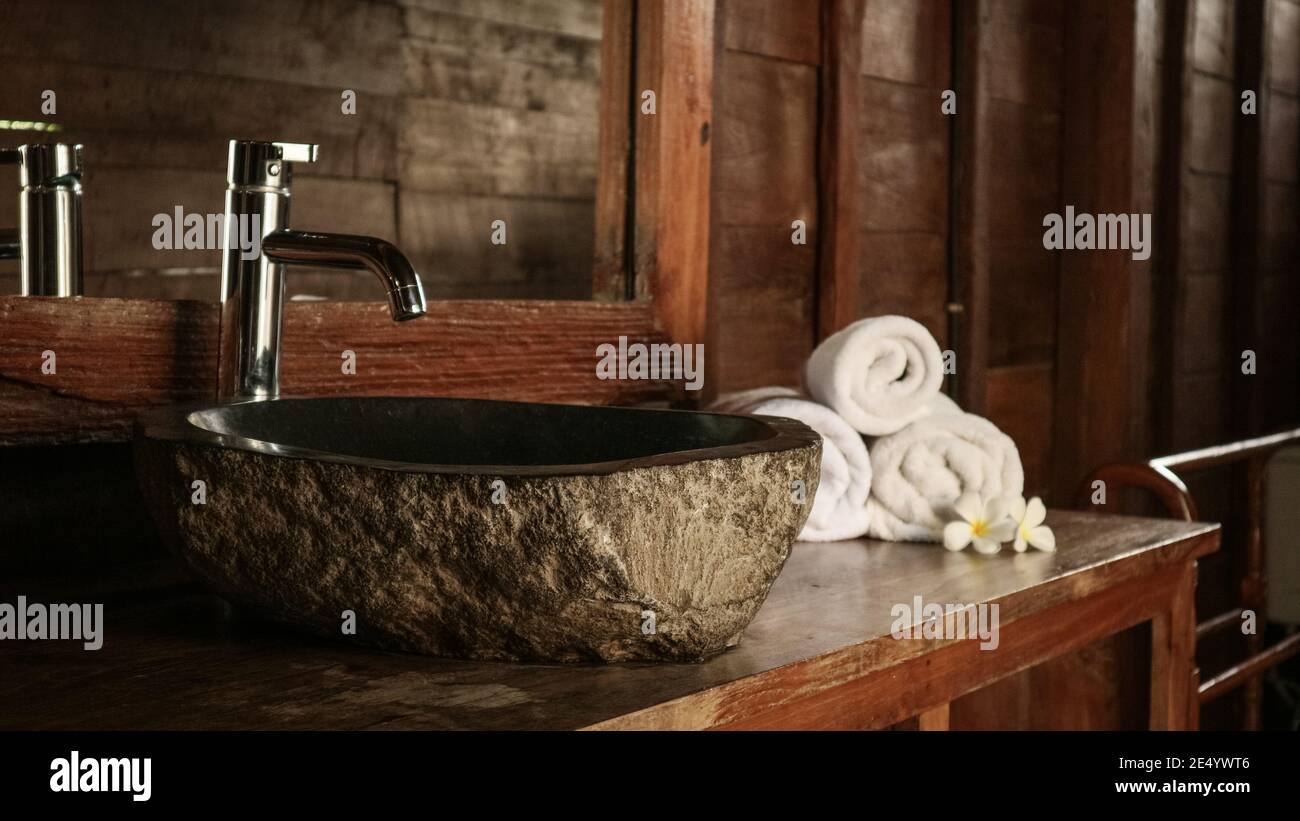 Bathroom with stone washbasin, mirror and towels in traditional ...