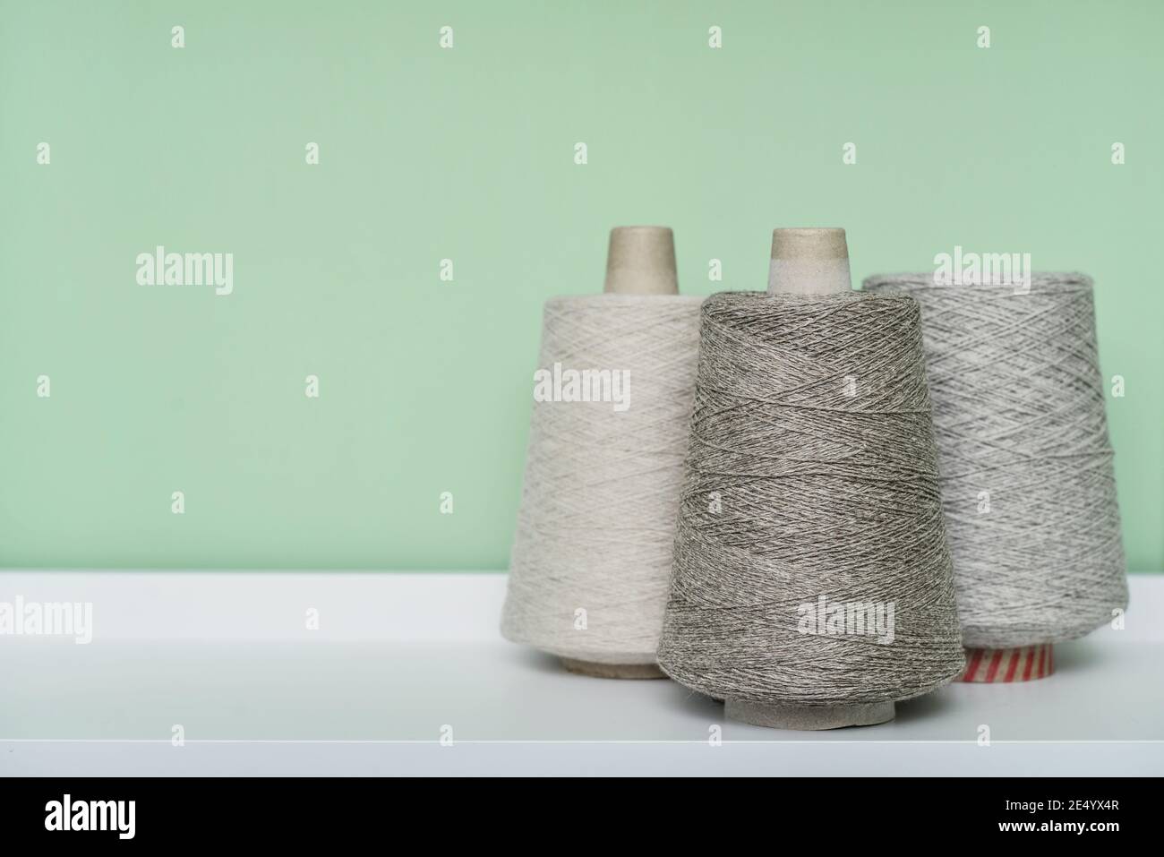 Set of colored yarn for knitting on cone on green background, with copy ...