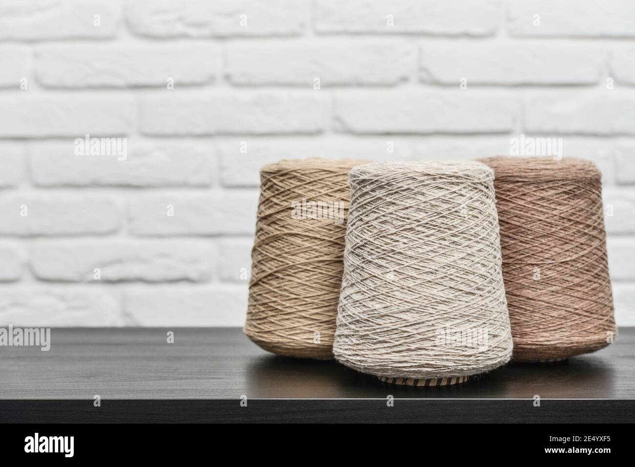 Set of colored yarn for knitting on cone on light background, with copy ...