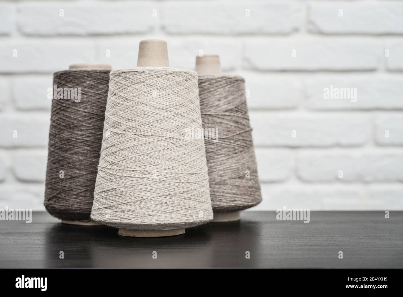 Set of colored yarn for knitting on cone on light background, with copy ...