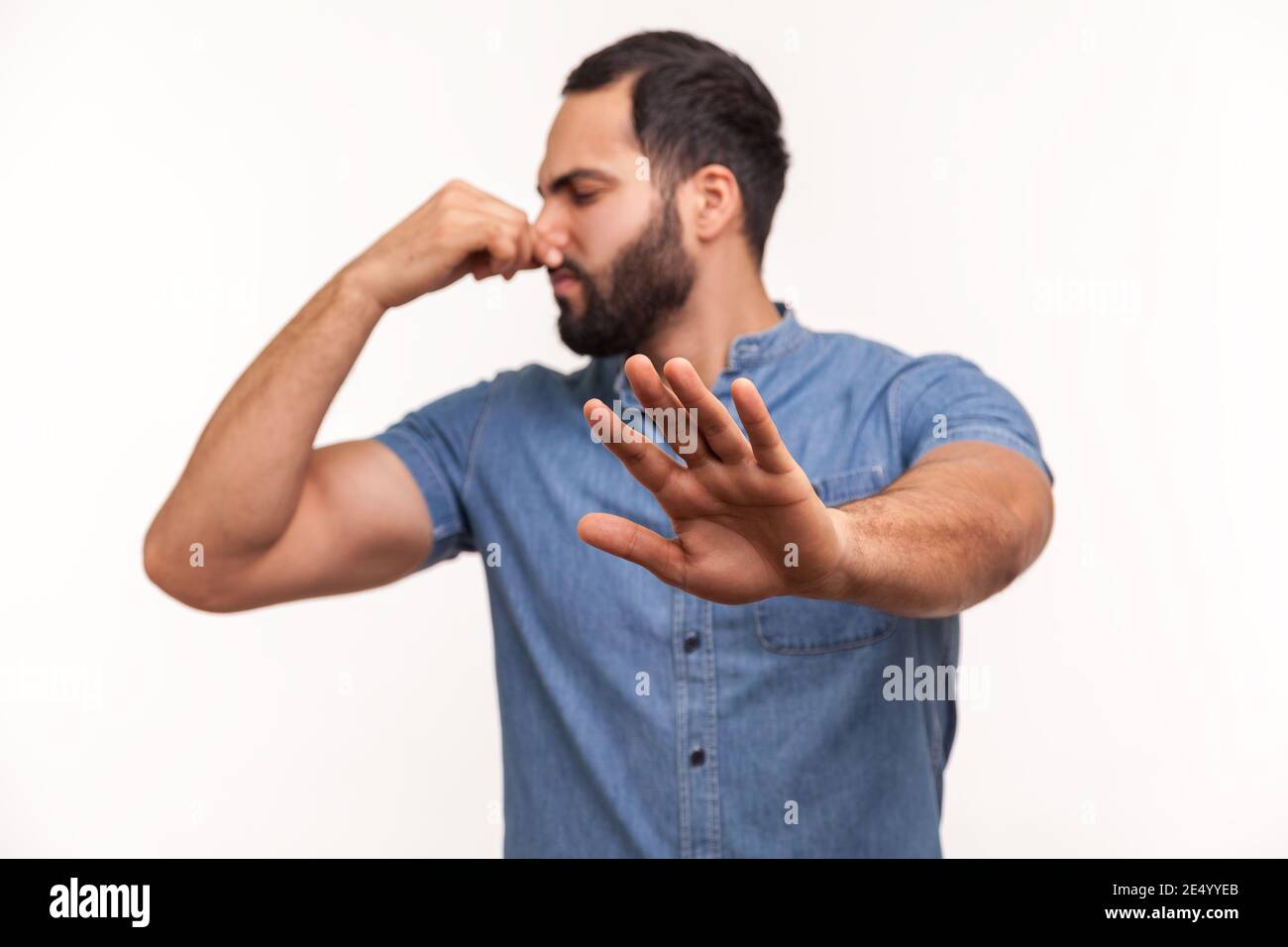 Confused unhappy bearded man grabbing nose with fingers and stretching hand out feeling ...