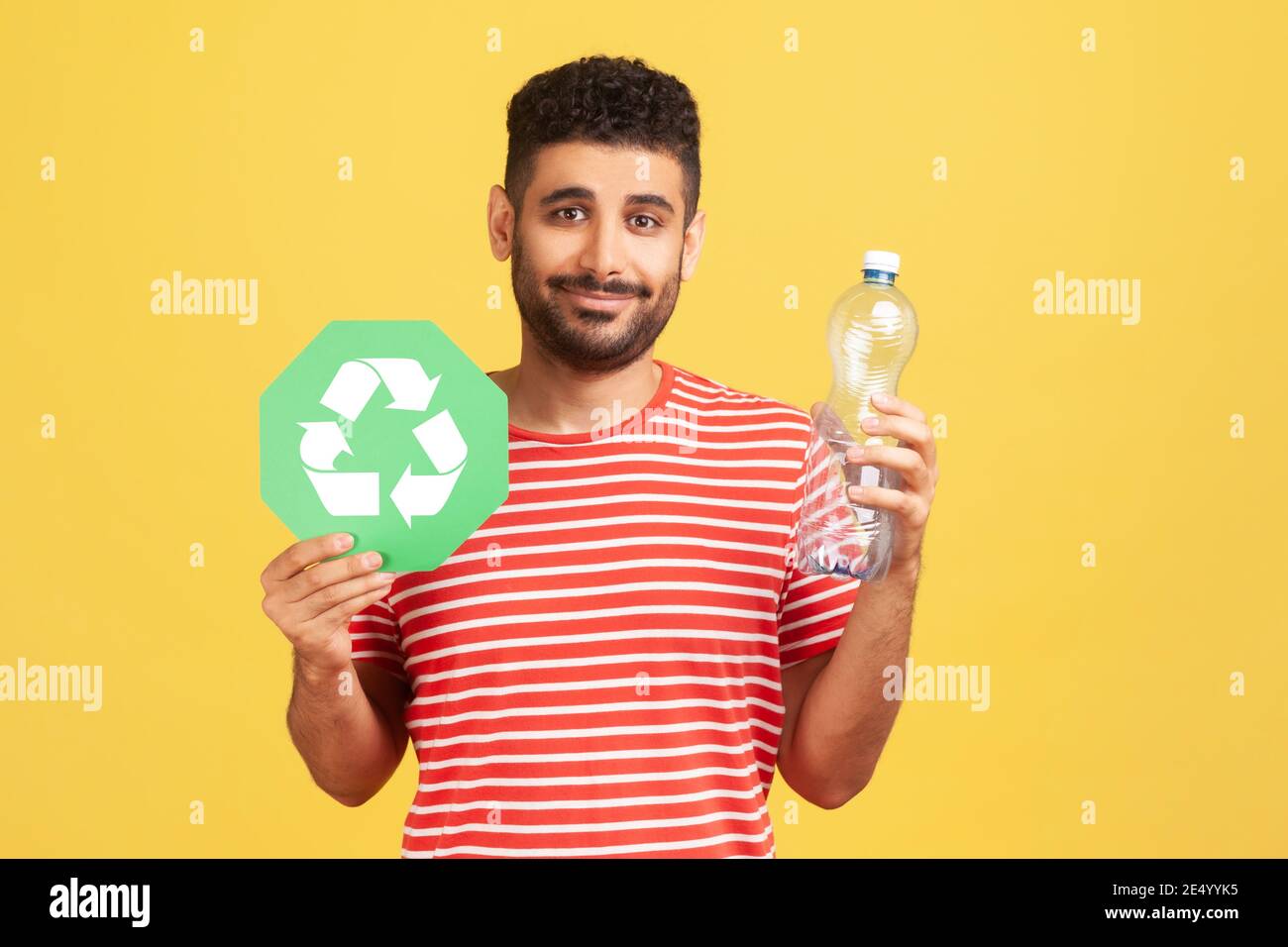 Smiling positive man with beard in striped t-shirt holding plastic ...