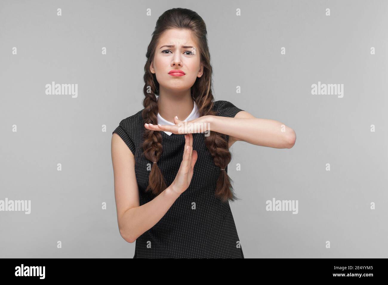 Well dressed woman showing time out sign at camera. Indoor, studio shot ...