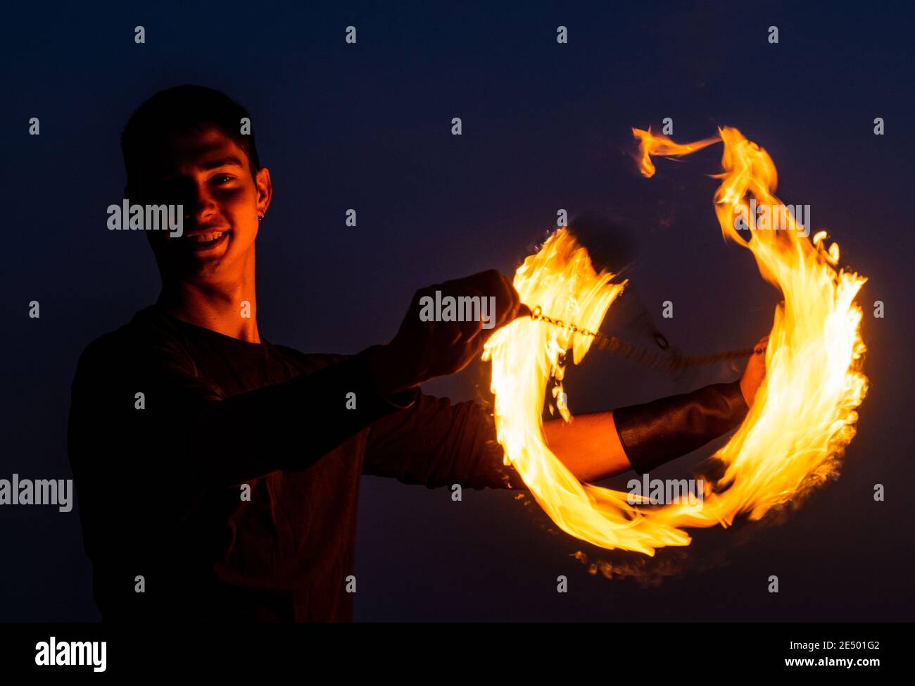Game of light and dark. Fire spinner at night. Happy male spinner spin ...