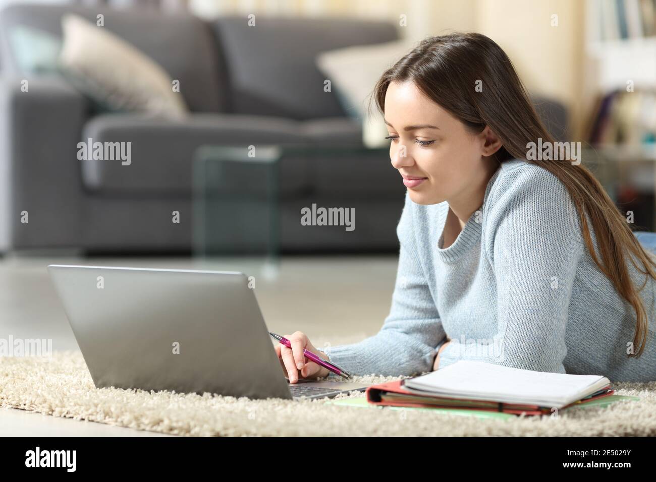 Satisfied student e-learning using laptop lying on the floor at home ...