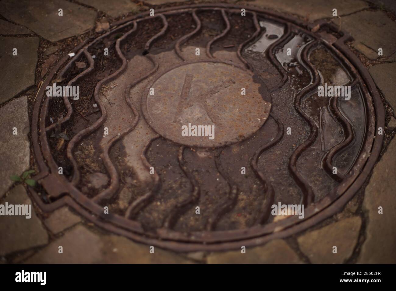 manhole with letter k wet after rain Stock Photo - Alamy