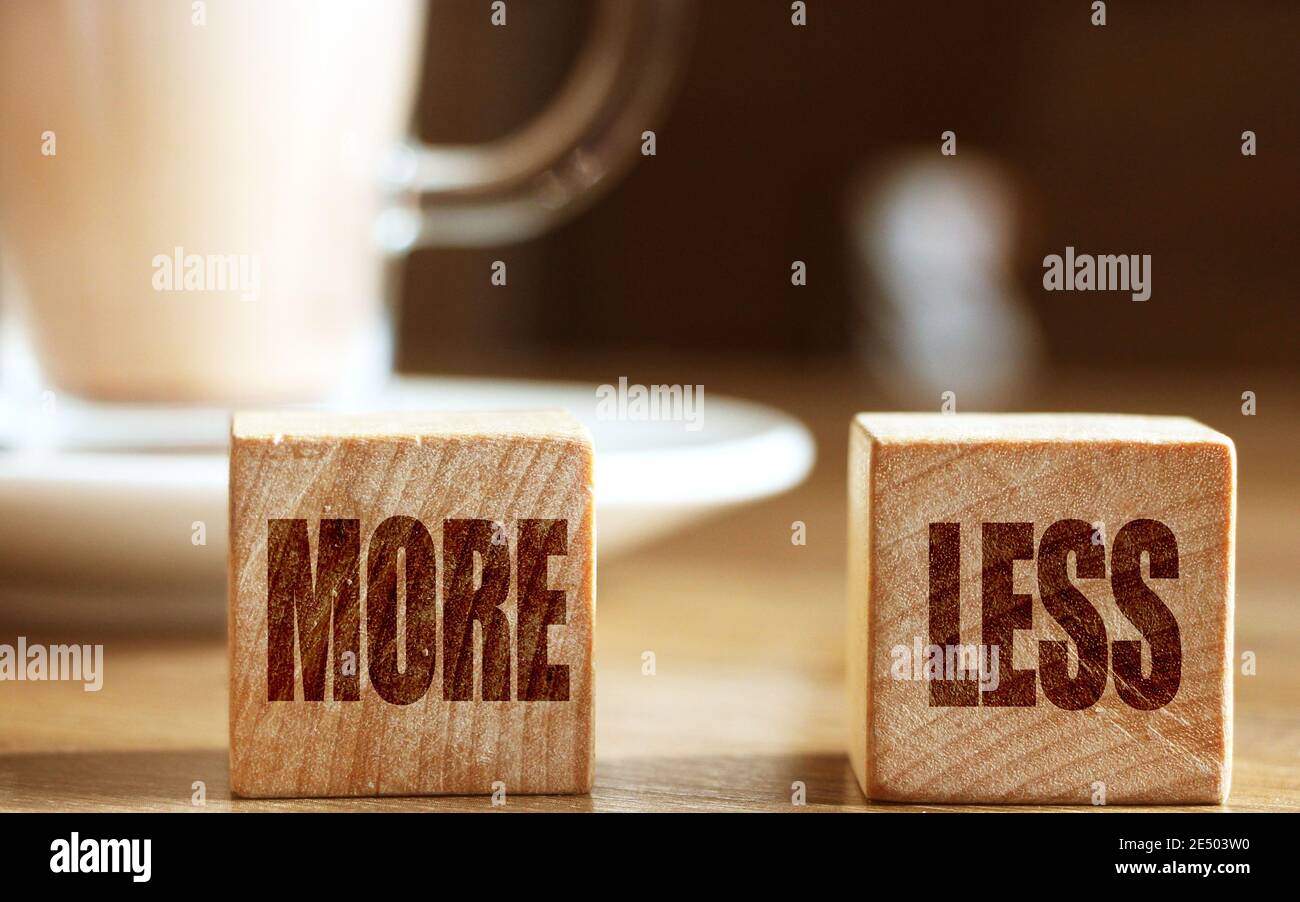 Wooden blocks on wooden table with More and Less signs. Decision making ...