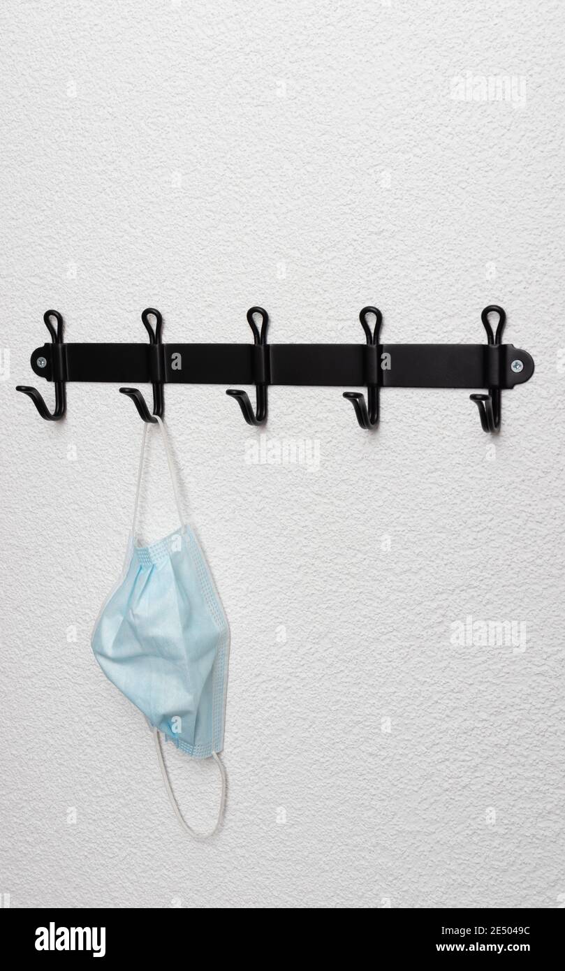 Surgical hygiene mask hanging from a hook in wardrobe. Concept of ...