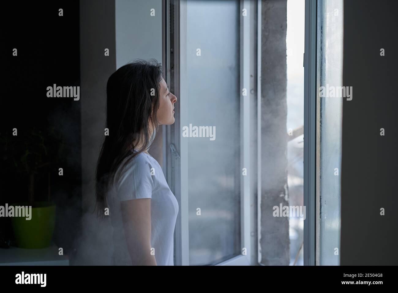 Cold winter weather. Woman step to window, open it and frosty air ...