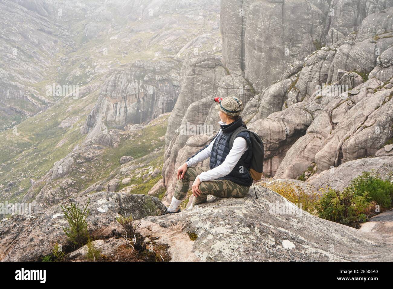 Young woman in sports clothing sitting on rocks enjoying the scenery of ...