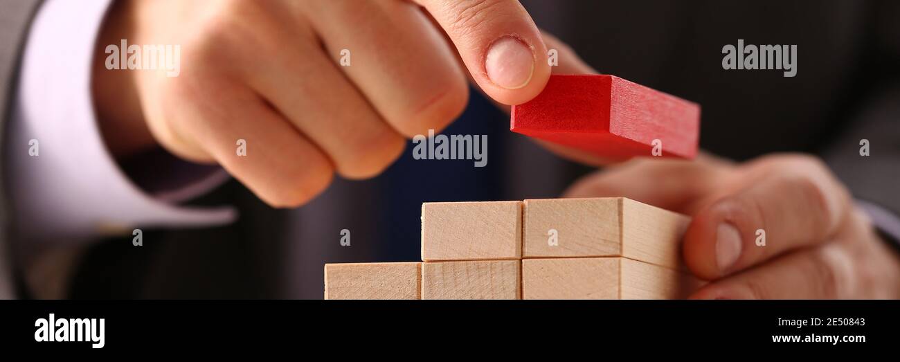 Man arranging wood block and stacking as tower by hand Stock Photo - Alamy