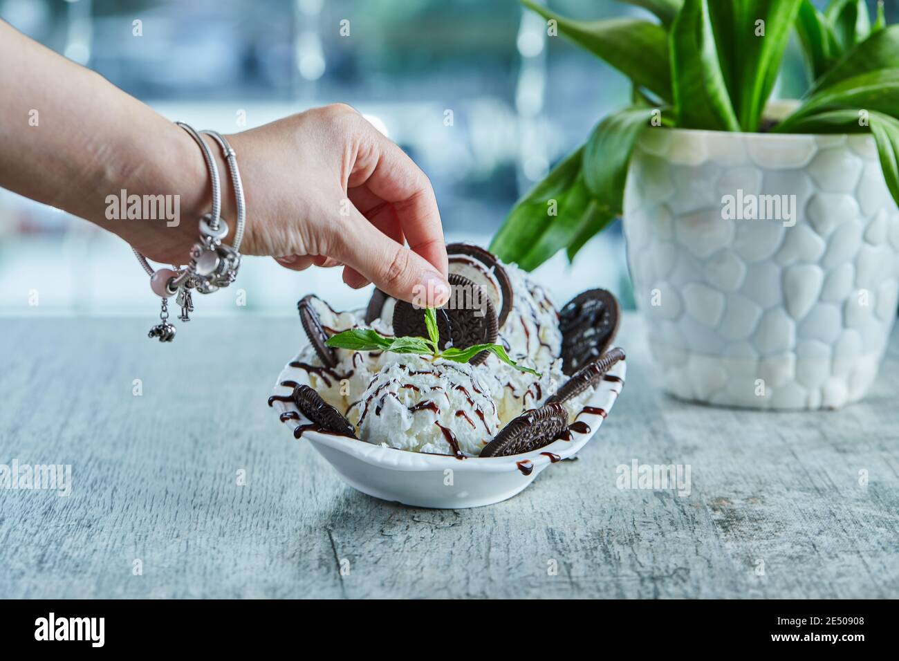 A woman hand holding a piece of oreo with ice-cream, chocolate syrup on ...