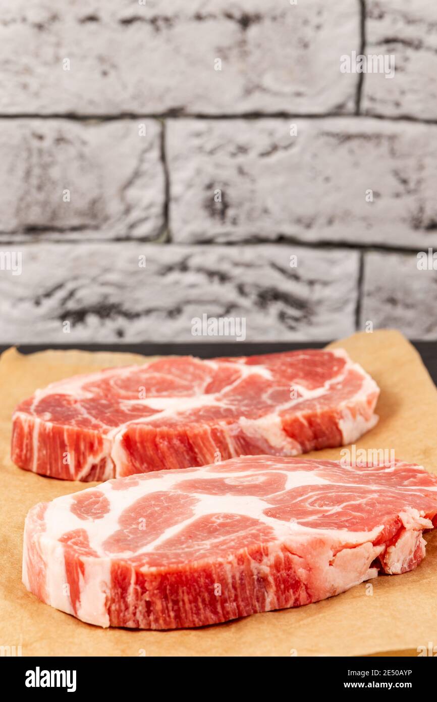 fresh raw marbled meat pork steak on brown parchment paper on black ...