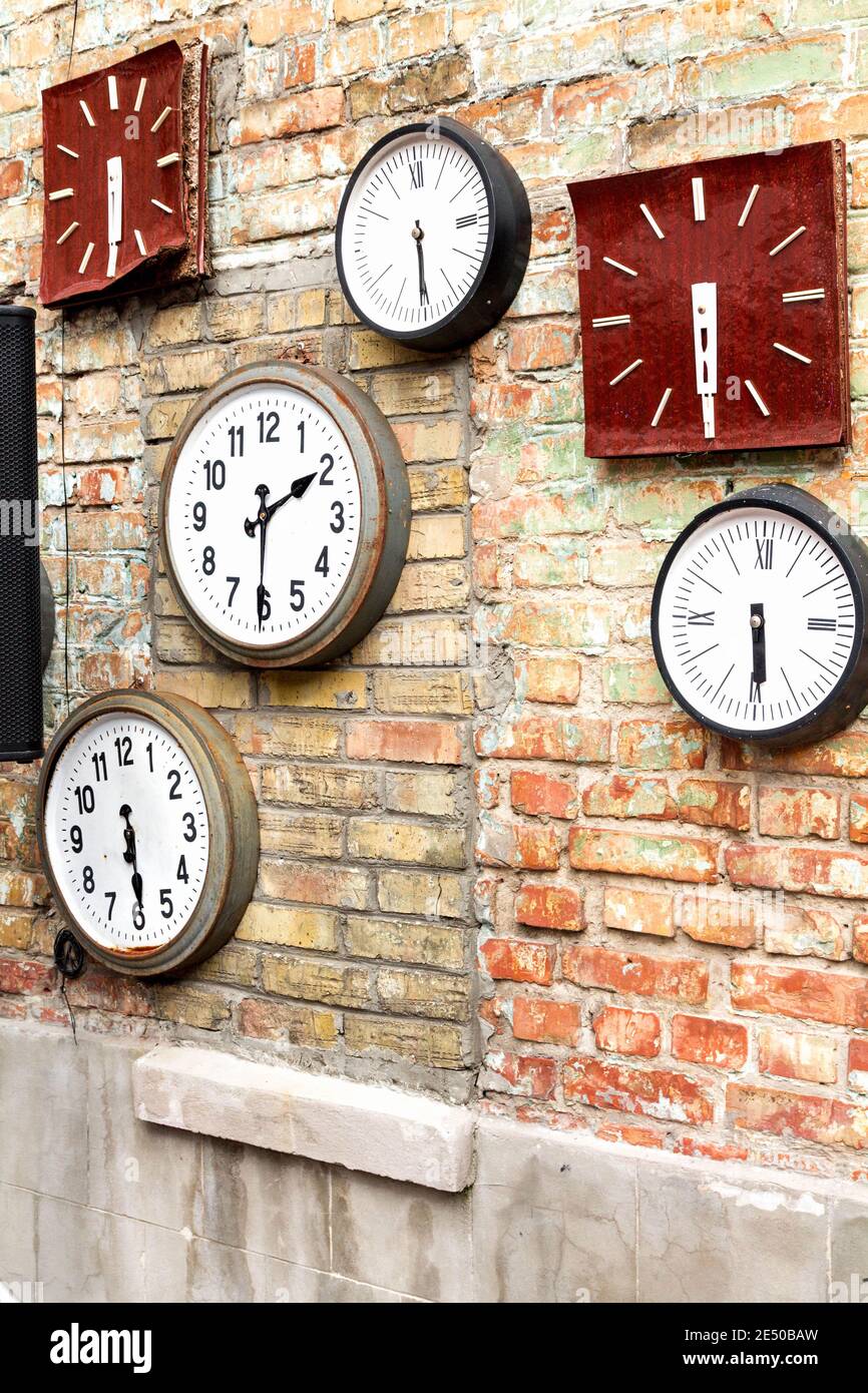 Clock on brick wall. Many watches with arrows Stock Photo - Alamy