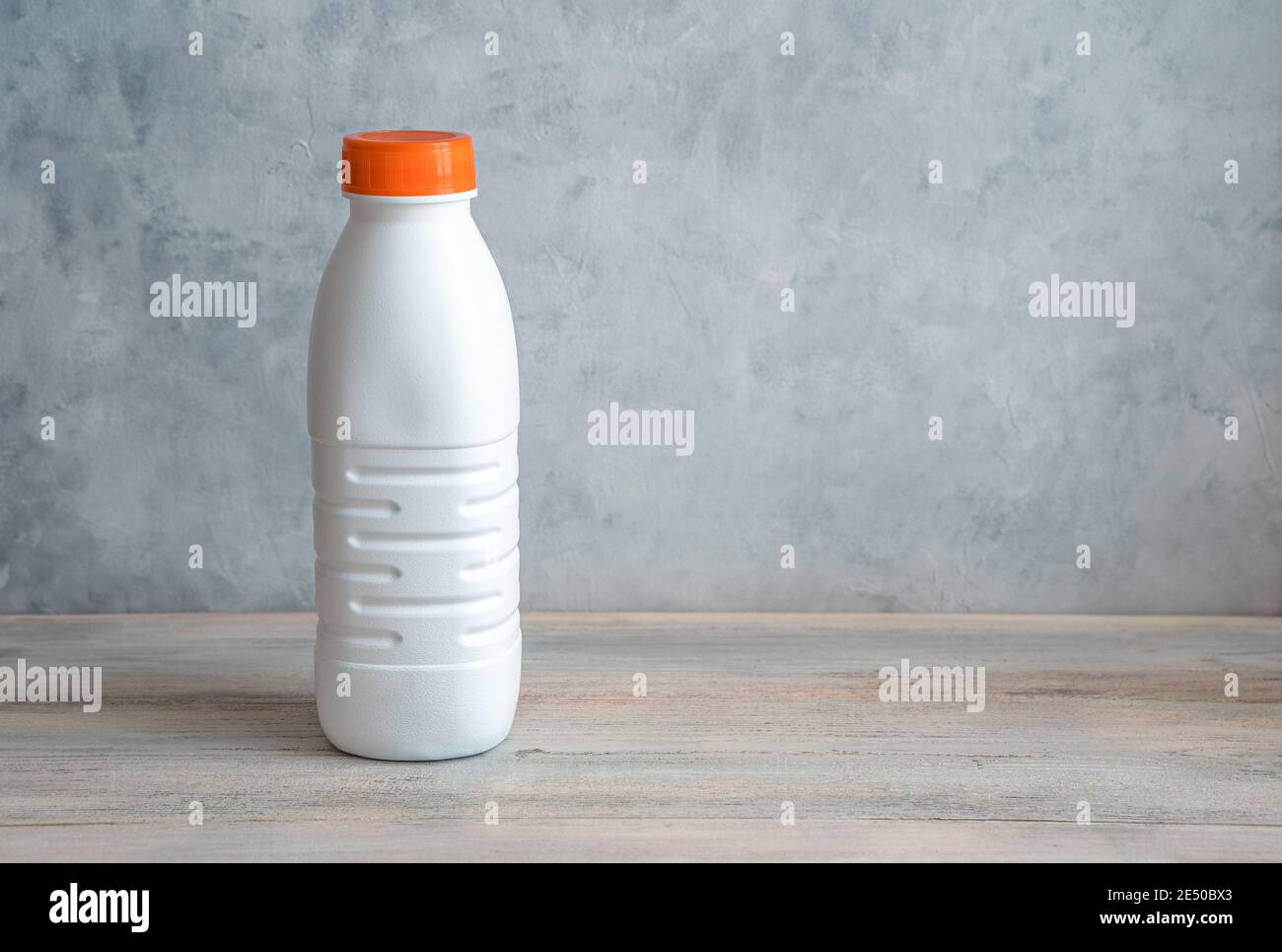 A white milk bottle with an orange lid on a gray background Stock Photo ...