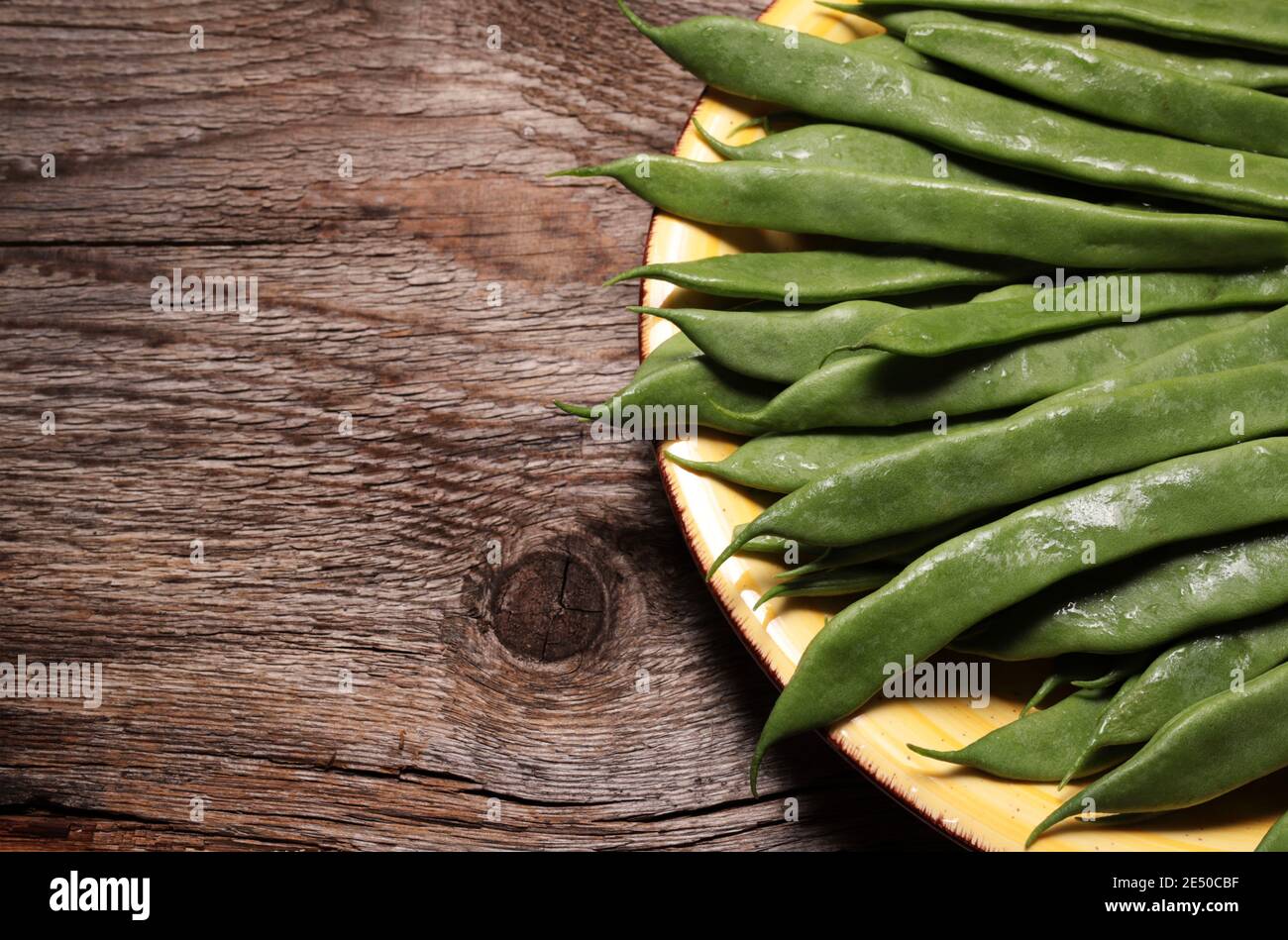 Piattoni green beans on a dish isolated on wooden background. Taccole ...