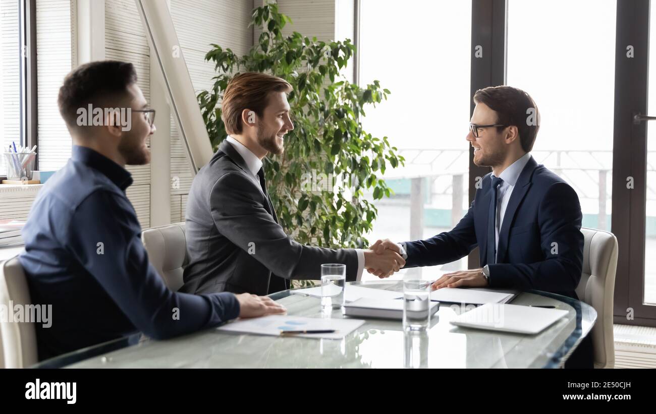 Happy business partners shaking hands, making deal after negotiations ...