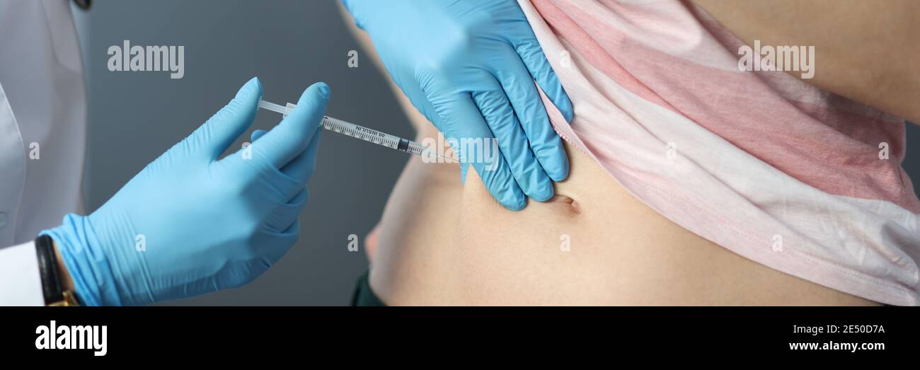 Doctor in rubber gloves making injection into patients skin fold close ...