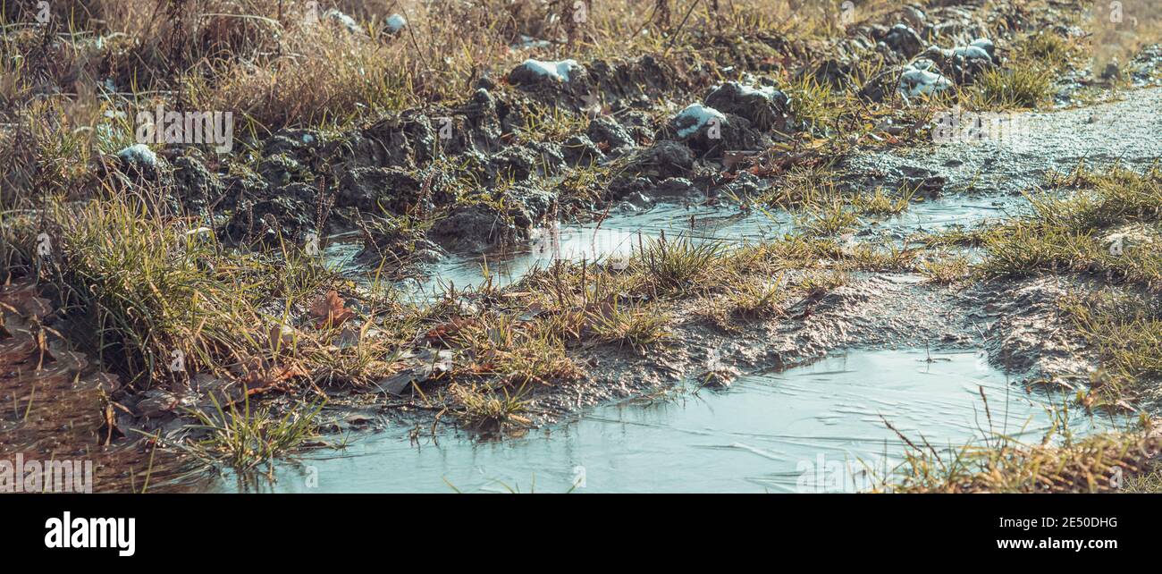 First snow and frost on a dirt road. Frozen dirt road and mud with snow ...