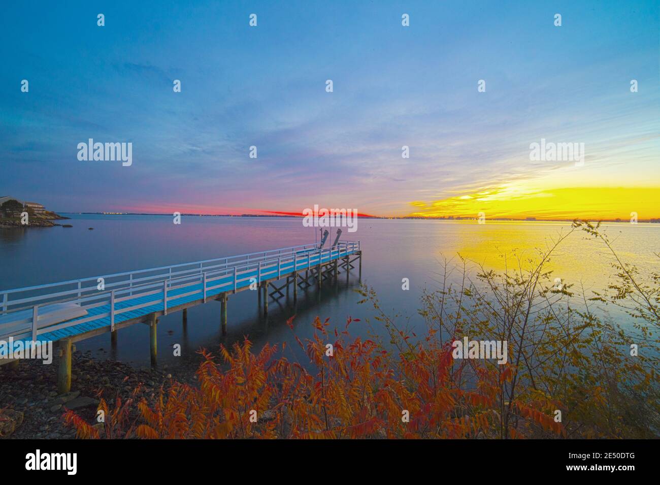 A Pier Extends into the Vivid Sunset Colors on the Ocean with the ...