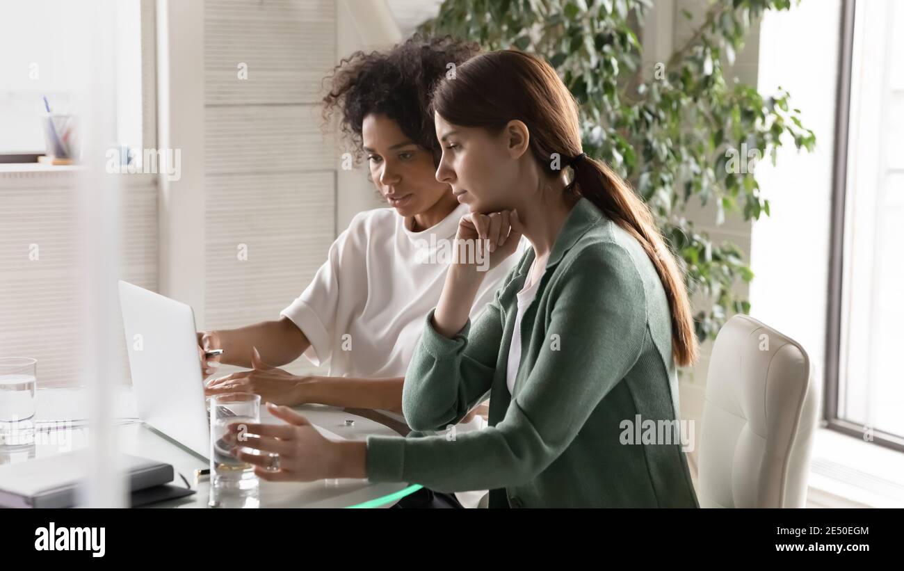 Confident African American mentor teaching new employee, using laptop ...