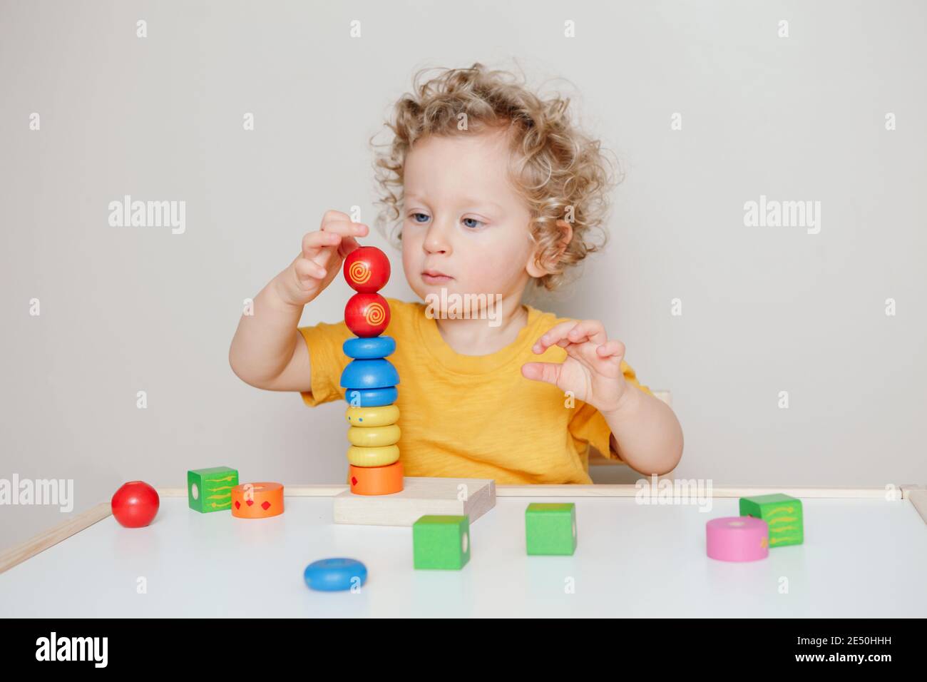Cute baby toddler playing with learning toy pyramid stacking blocks at ...