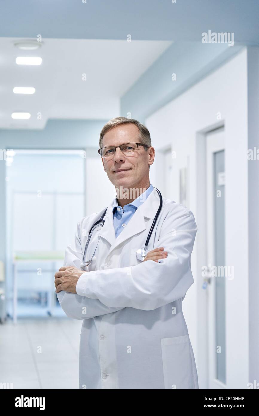 Happy old 60s doctor therapist standing in hospital looking at camera ...