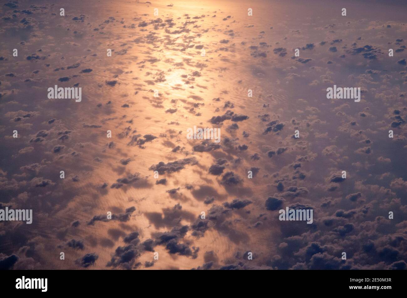 Aerial view of the land below as seen from high altitude, with fluffy ...