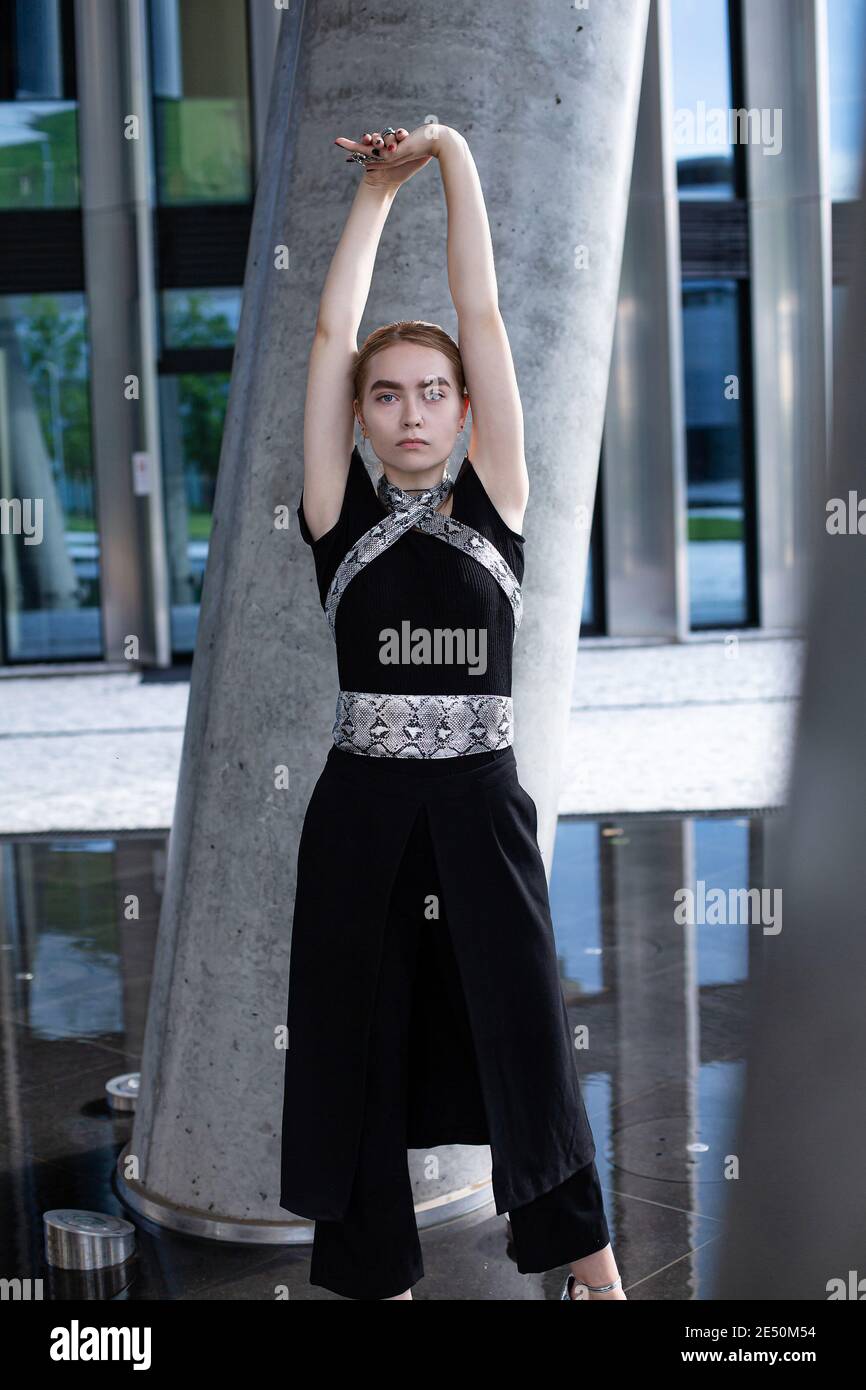 Young white model standing with city building background in black dress ...
