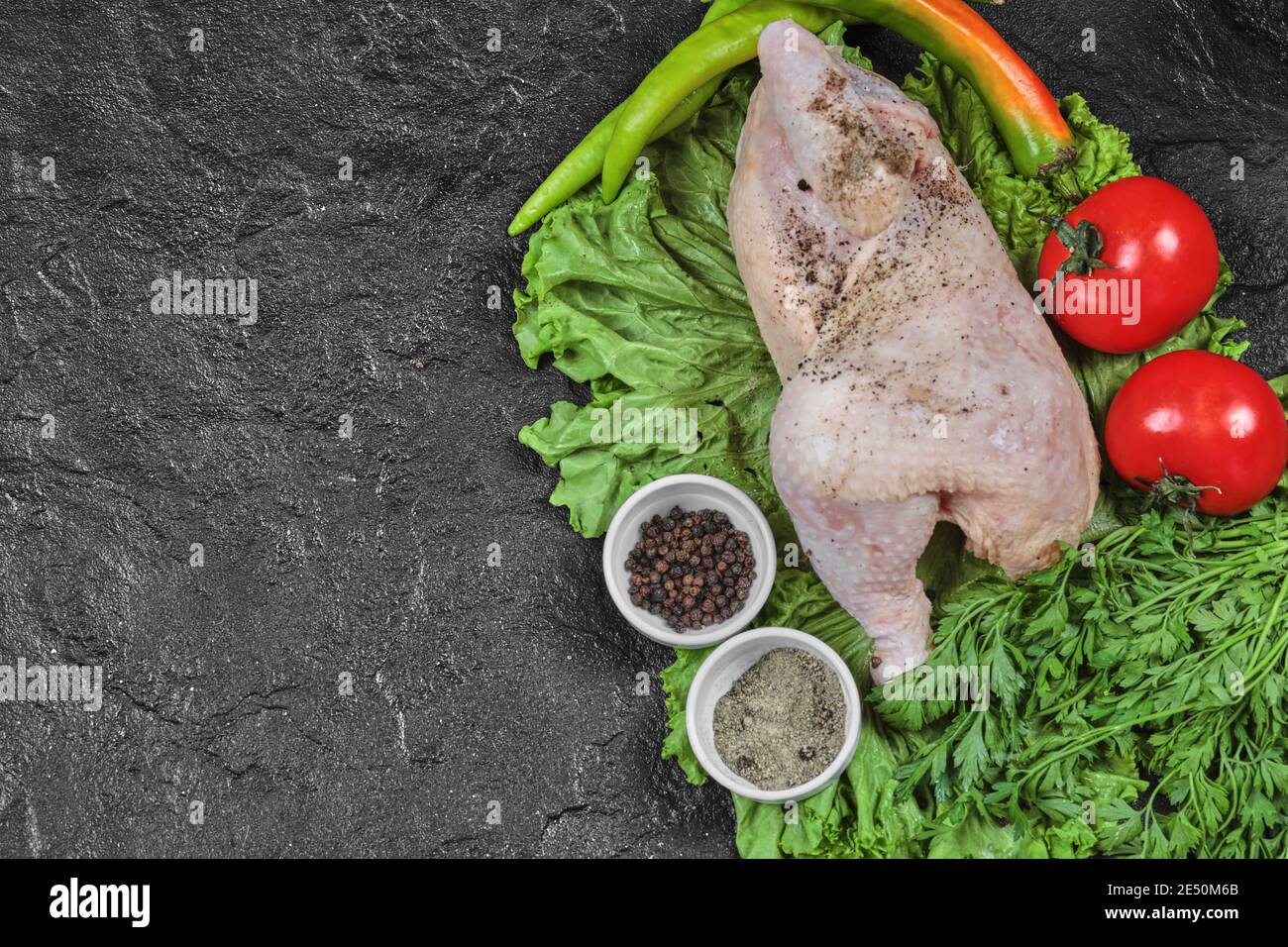 Raw chicken on dark background with bunch of fresh vegetables and ...